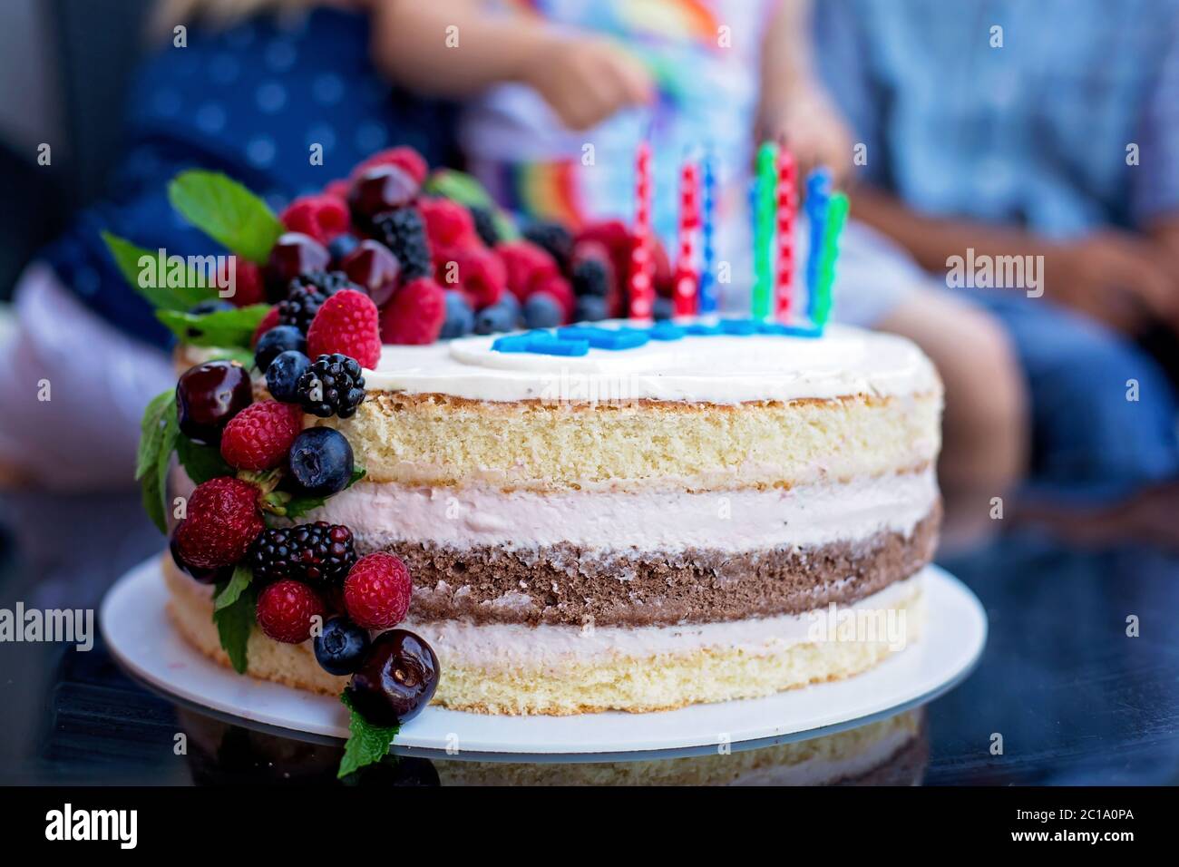 Homemade kids birthday cake with lots of fruits on top, cherries ...