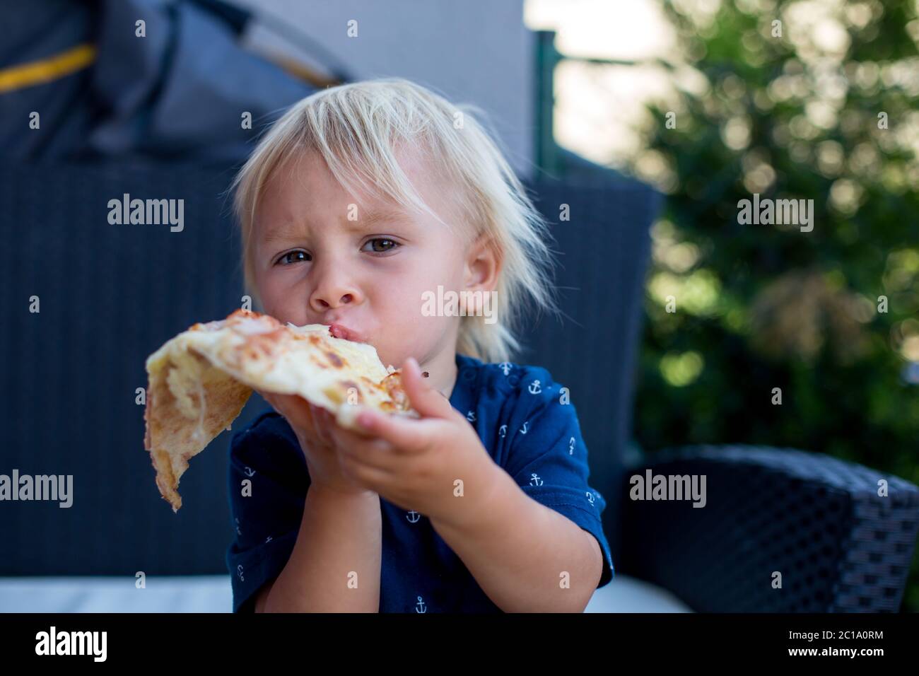 Cute little Caucasian kid eating pizza. Hungry child taking a bite from ...
