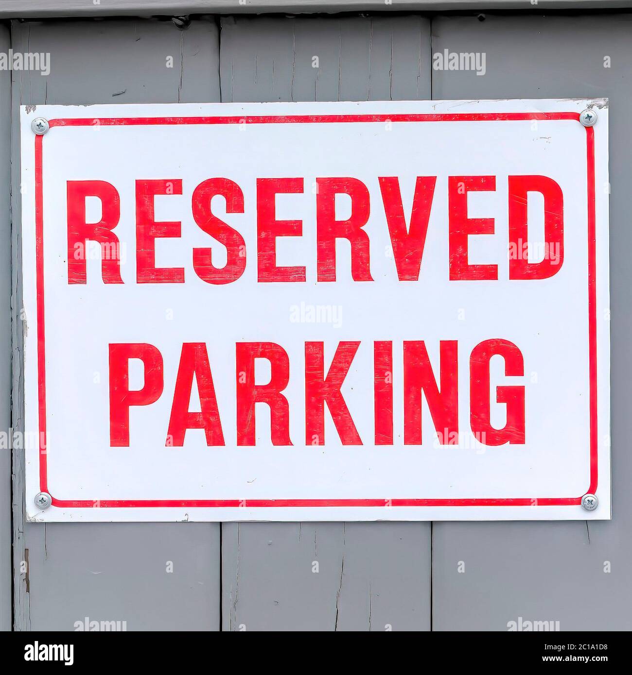 Square Reserved Parking sign board on a gray wooden wall topped with ...