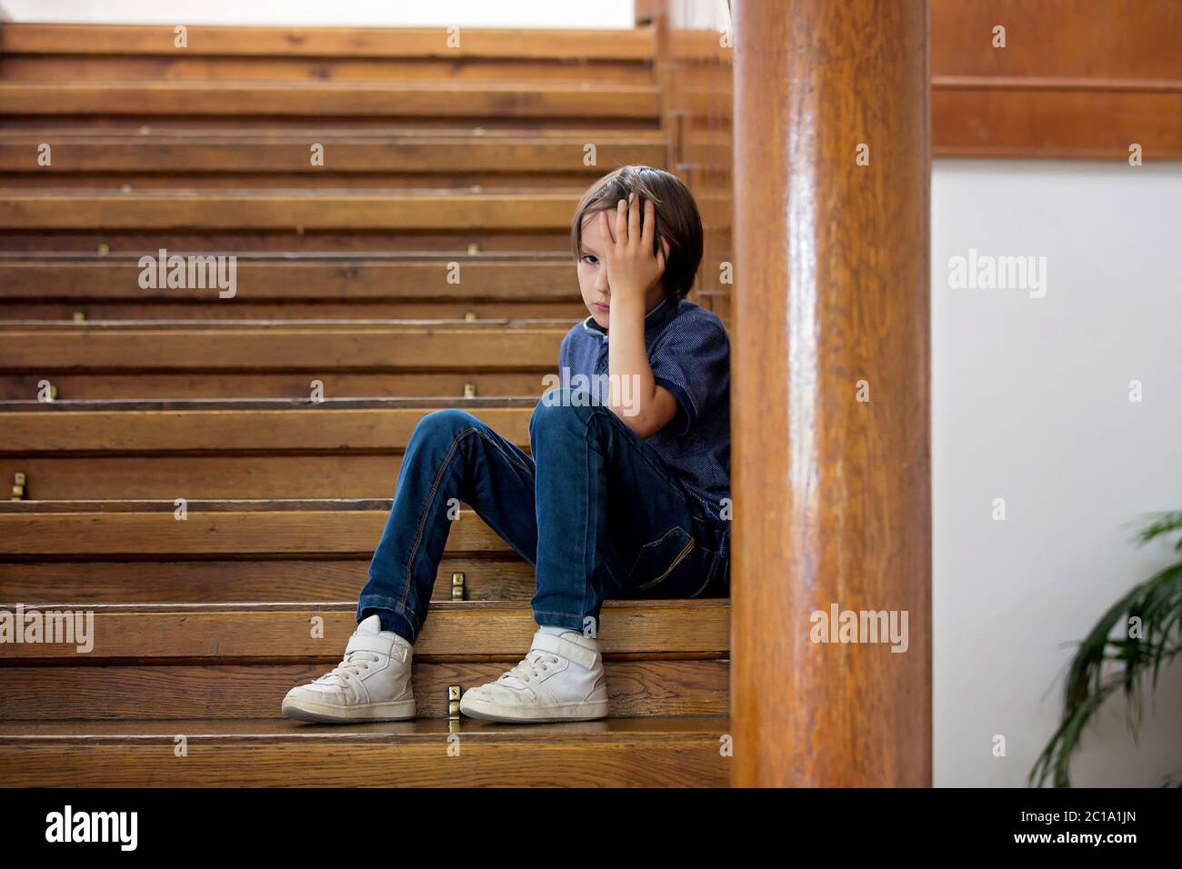 Sad child, sitting on a staircase in a big house, concept for bullying ...