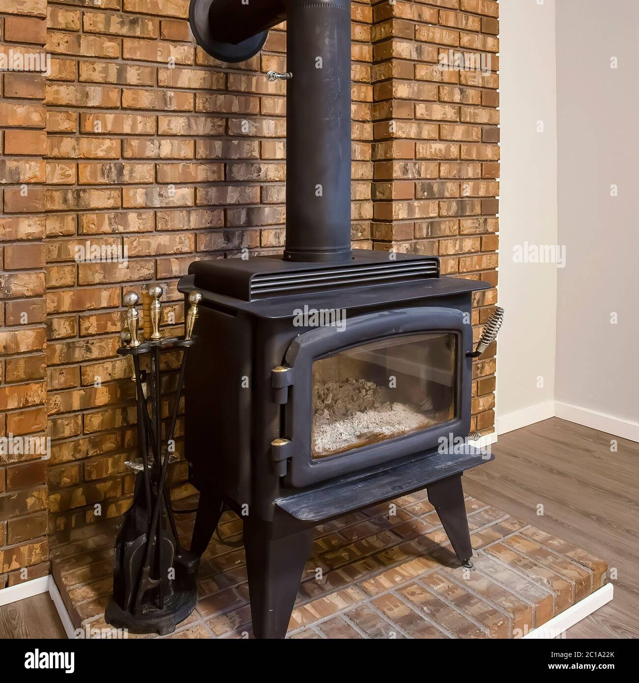Square frame Wood burning stove with pipe connected to the brick wall ...