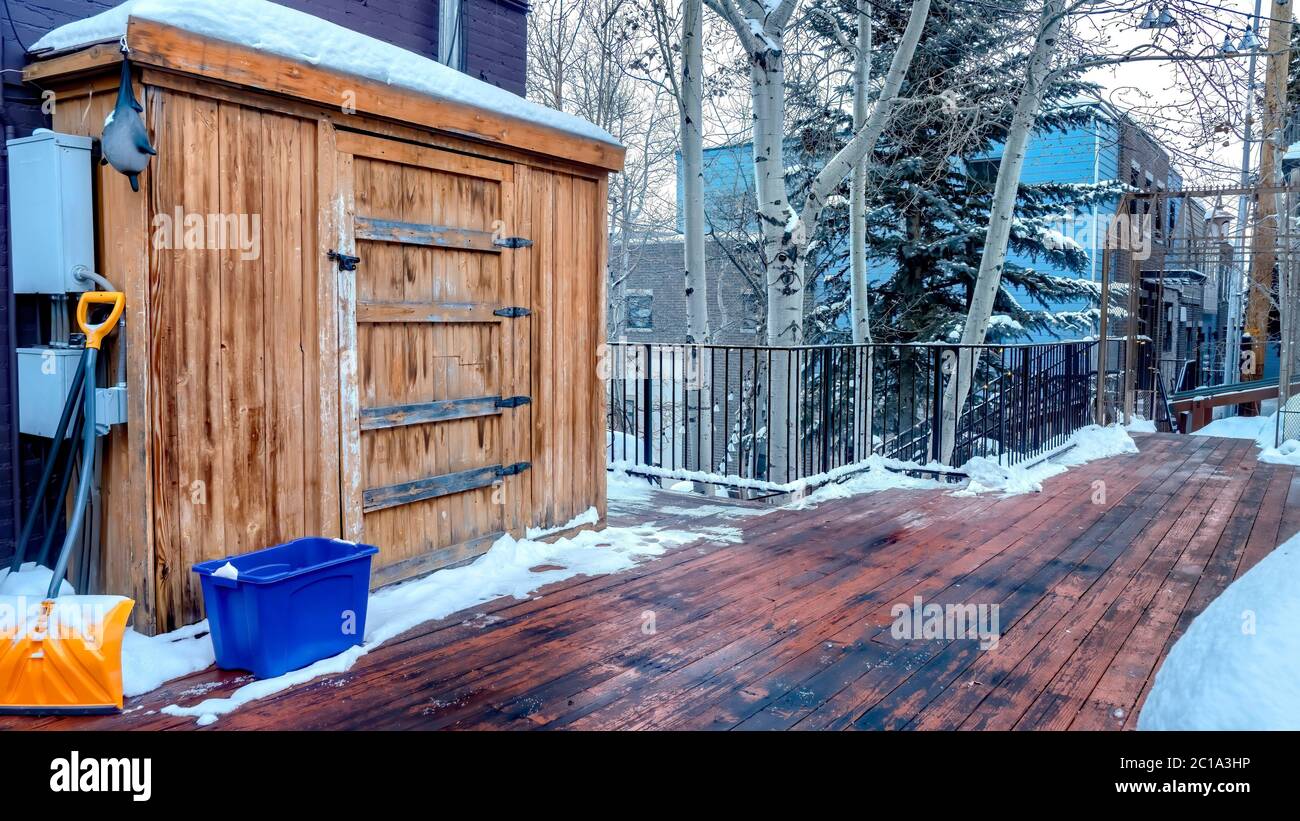 Panorama Wooden deck with snow shovel and bucket against storage ...