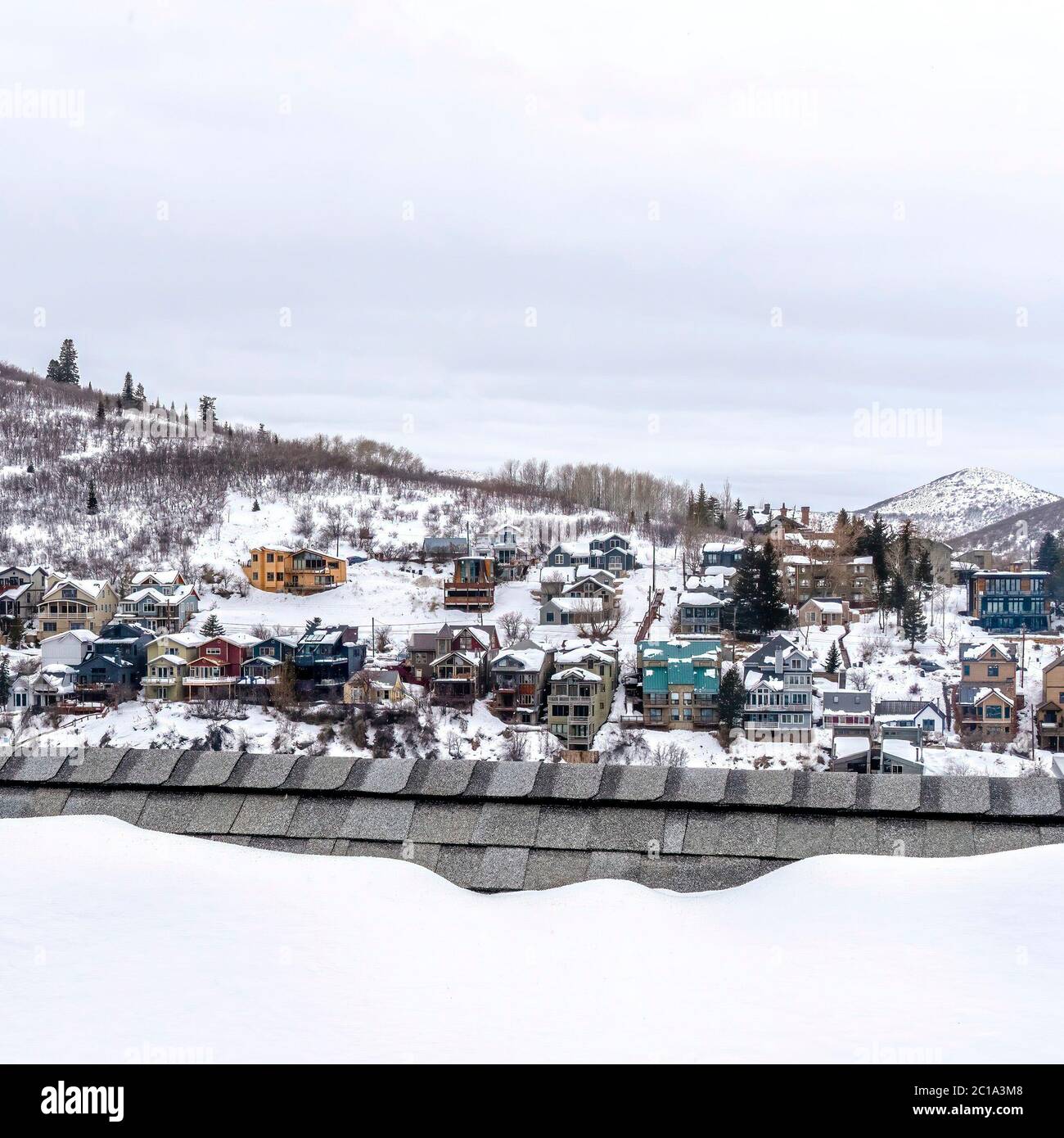Square crop Gray snowy roof against colorful homes on frosted hill in ...