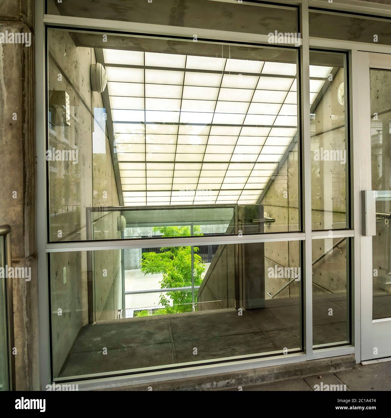 Square Glass door and wall with view of slanted frosted roof over ...