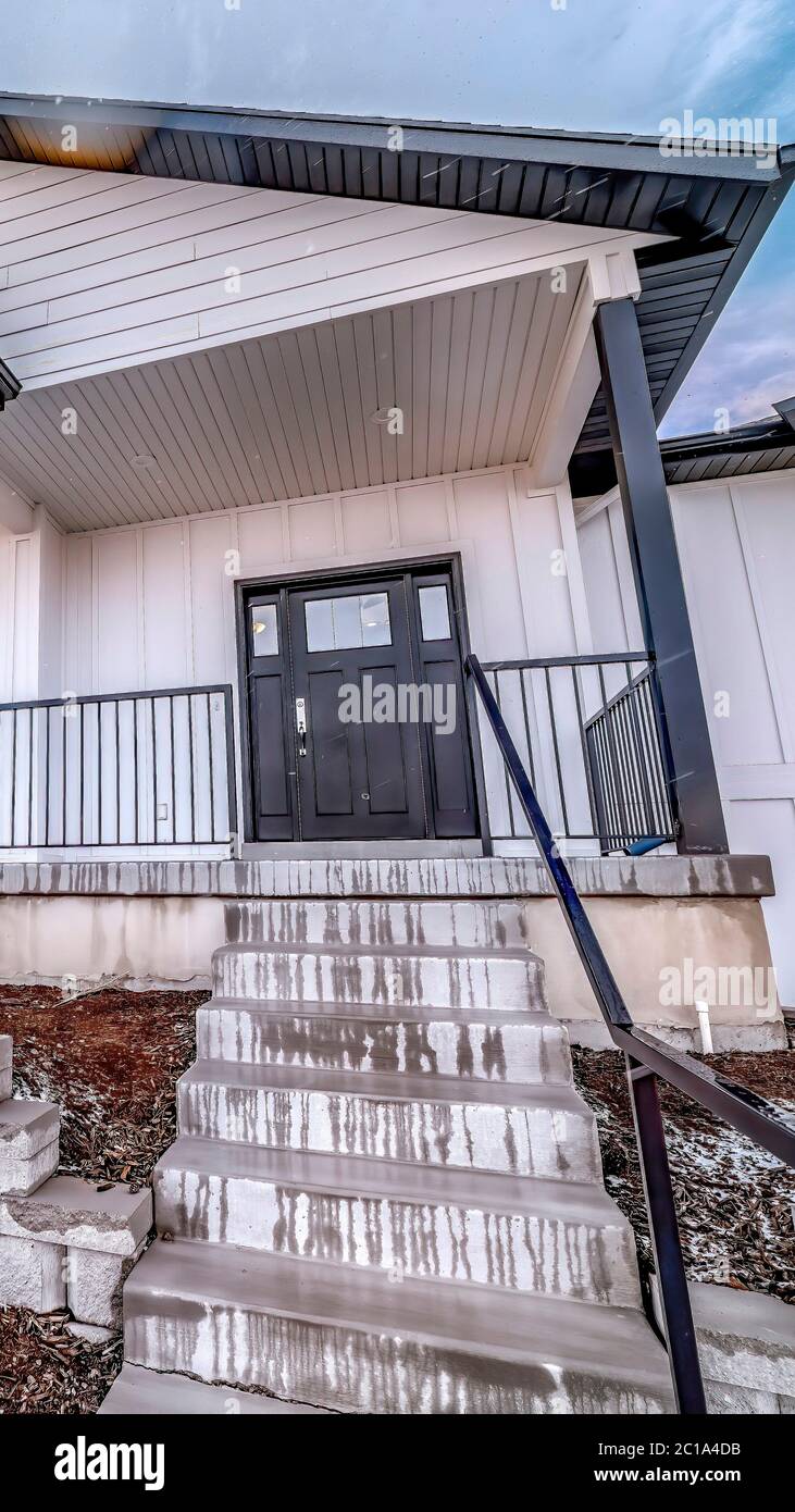 Vertical crop Home exterior with snow dusted yard against bright blue ...