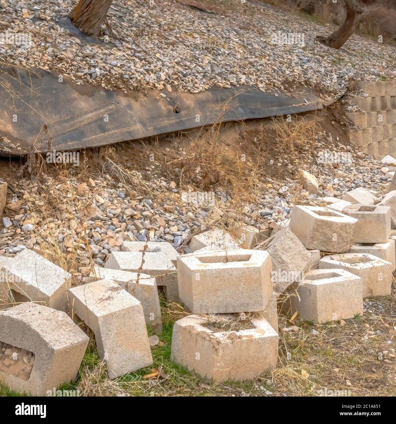 Square Conctere blocks of a collapsed low retaining wall lining a slope ...