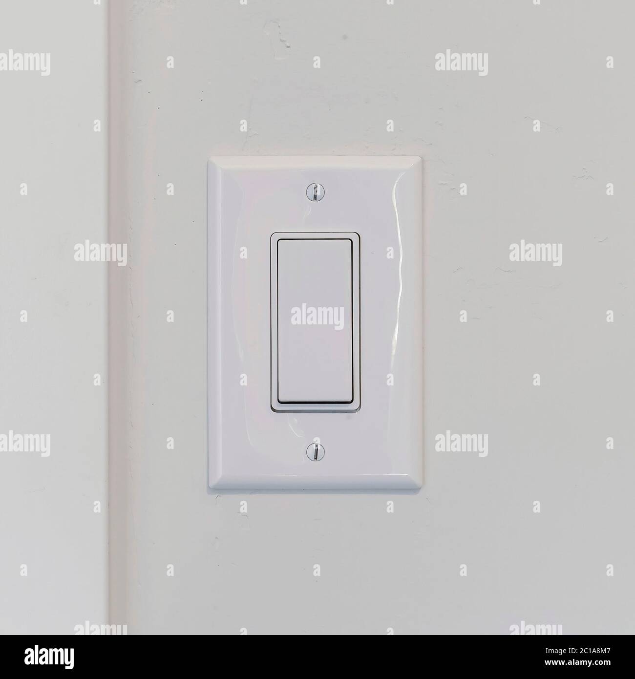 Square Electrical rocker light switch on white wall against blurry door ...