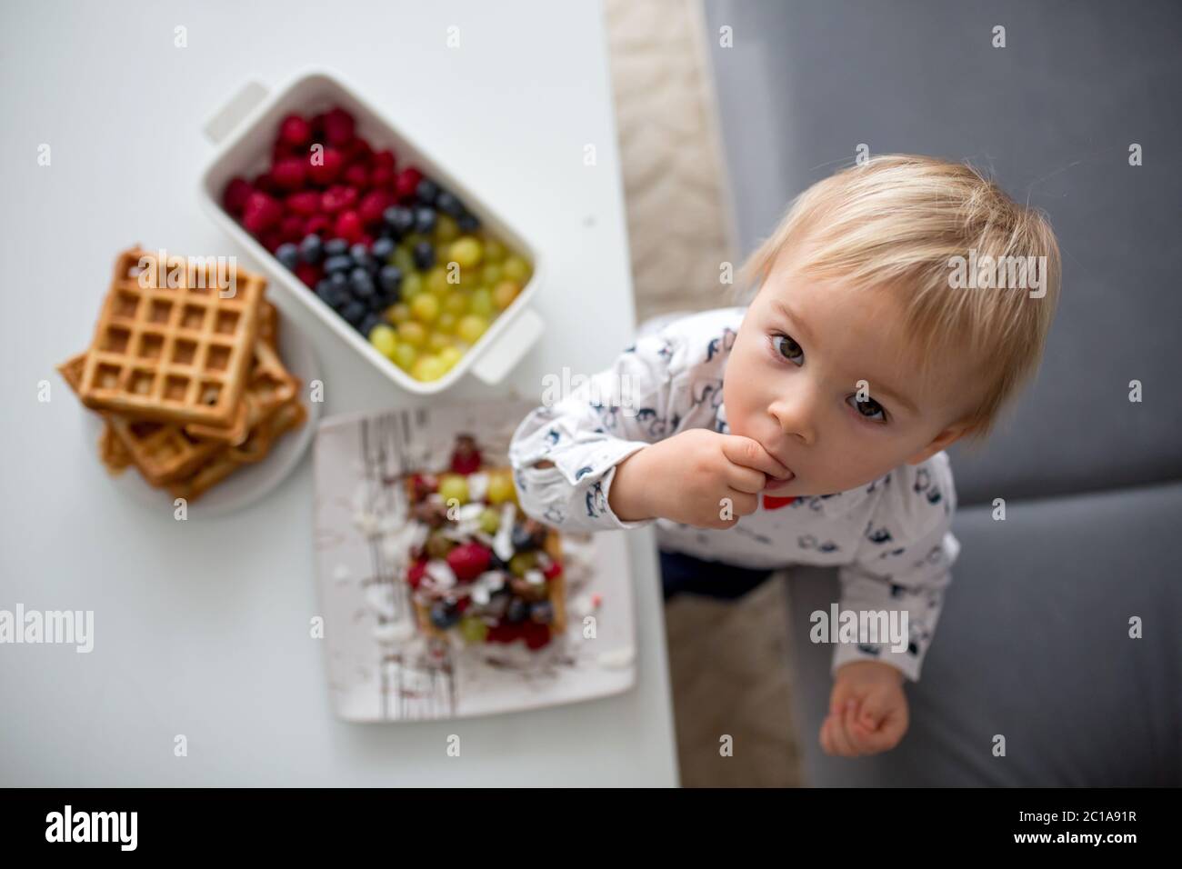 Sweet toddler birthday boy, eating belgian waffle with raspberries ...