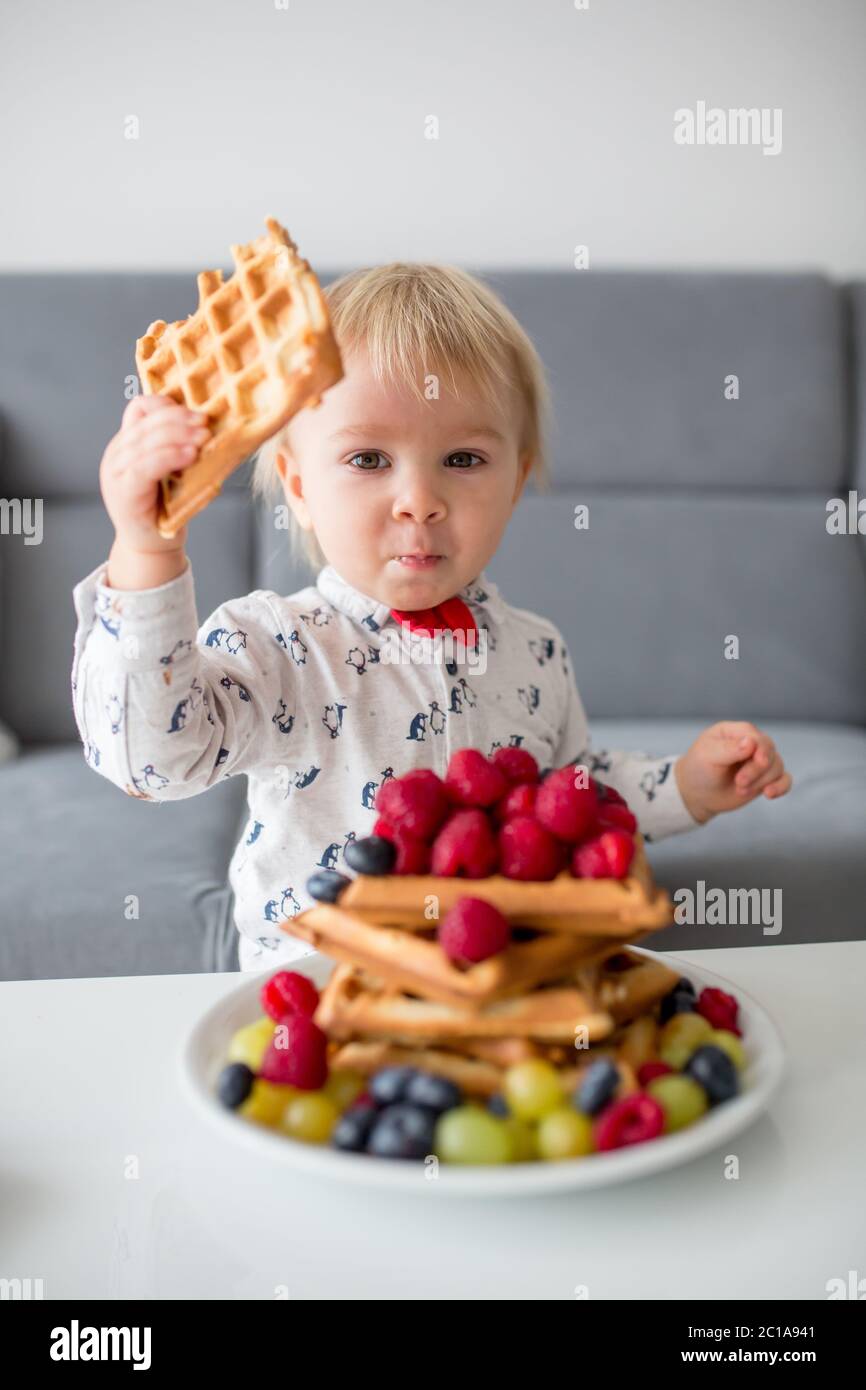 Sweet toddler birthday boy, eating belgian waffle with raspberries ...