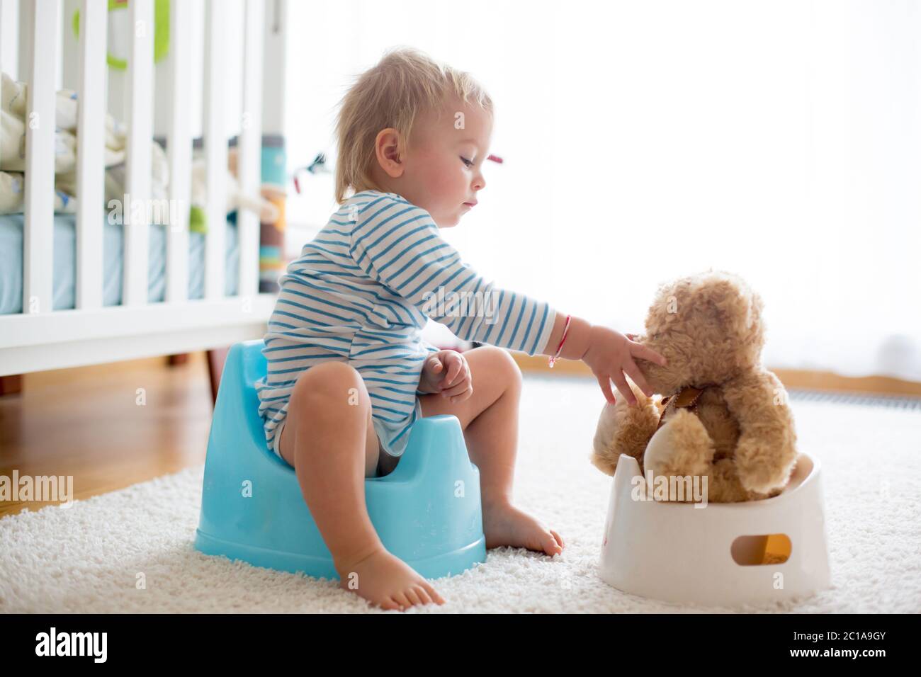 Cute toddler boy, potty training, playing with his teddy bear on potty ...