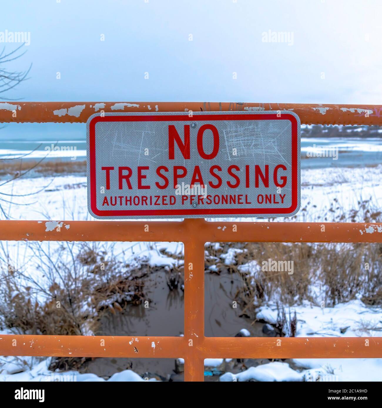 Square crop No Trespassing signage on a fence against Utah Lake and ...