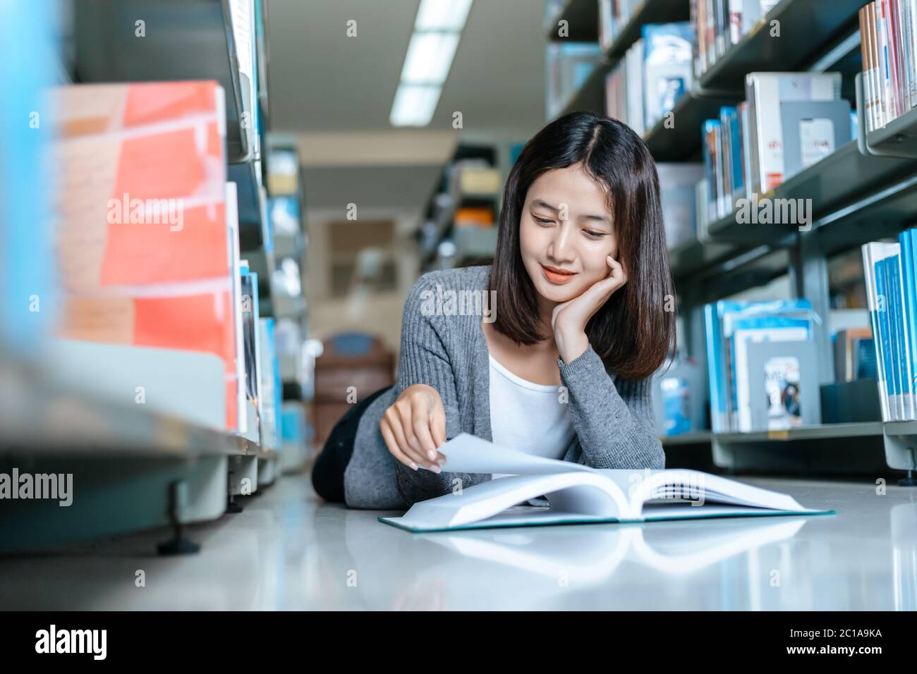 Student college opening and reading a book at library Stock Photo - Alamy