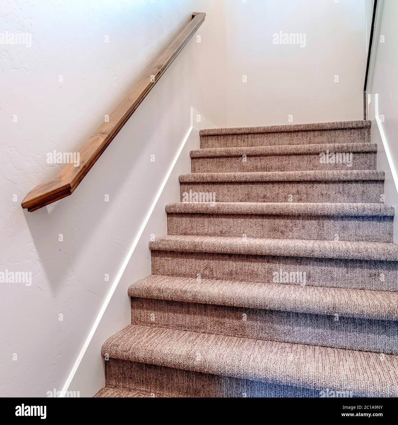 Square frame Carpeted indoor staircase of home with brown handrail ...