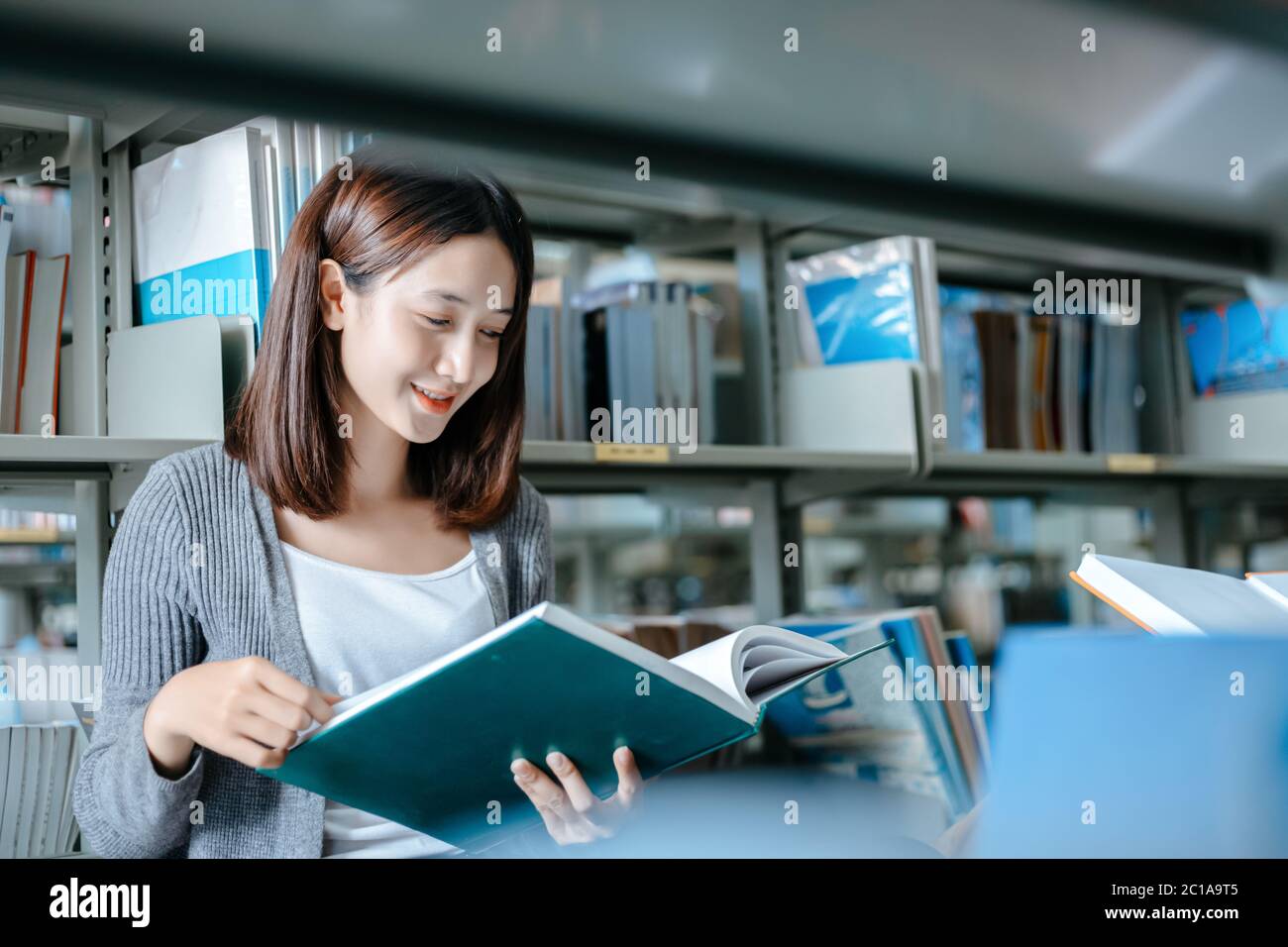 Student college opening and reading a book at library Stock Photo - Alamy