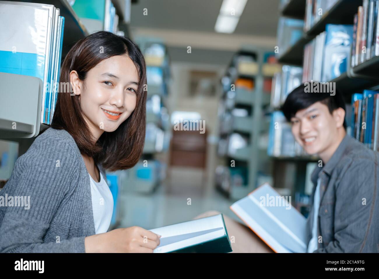 Student college opening and reading a book at library Stock Photo - Alamy