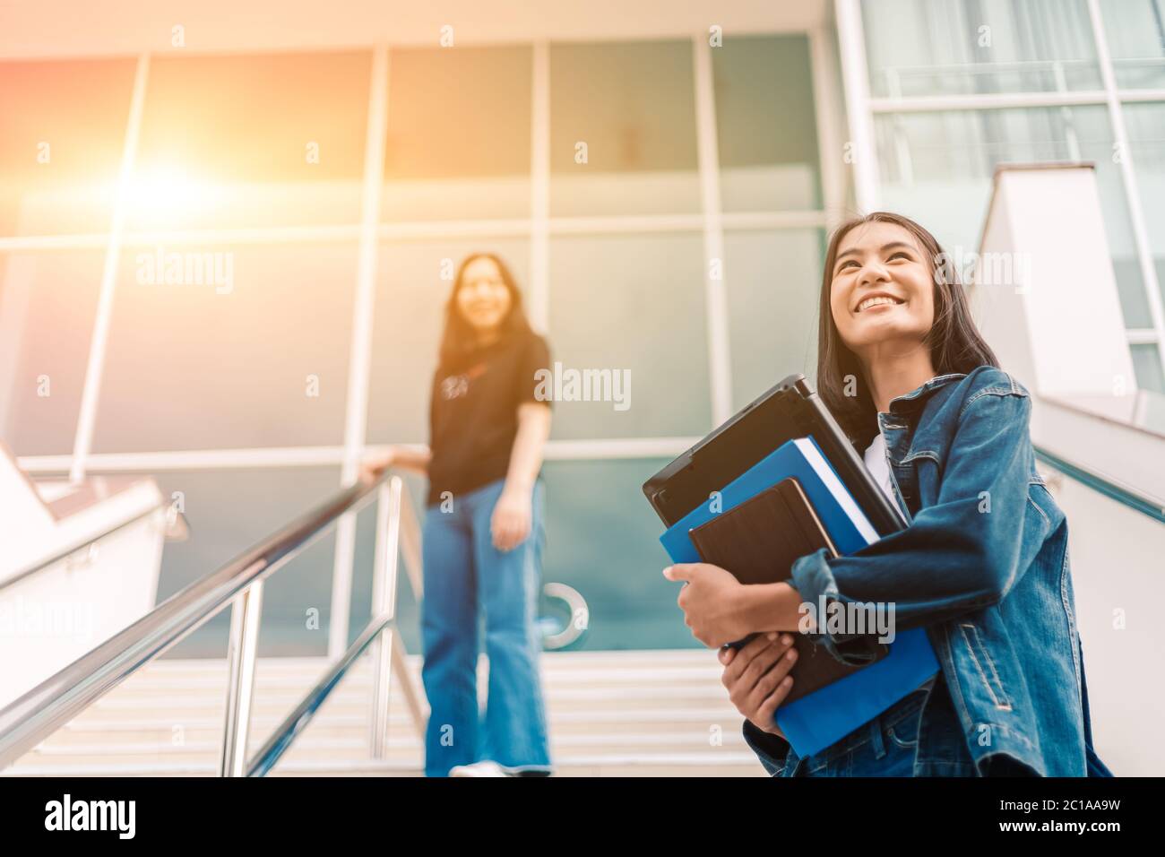 Student hold book and laptop in university Stock Photo - Alamy