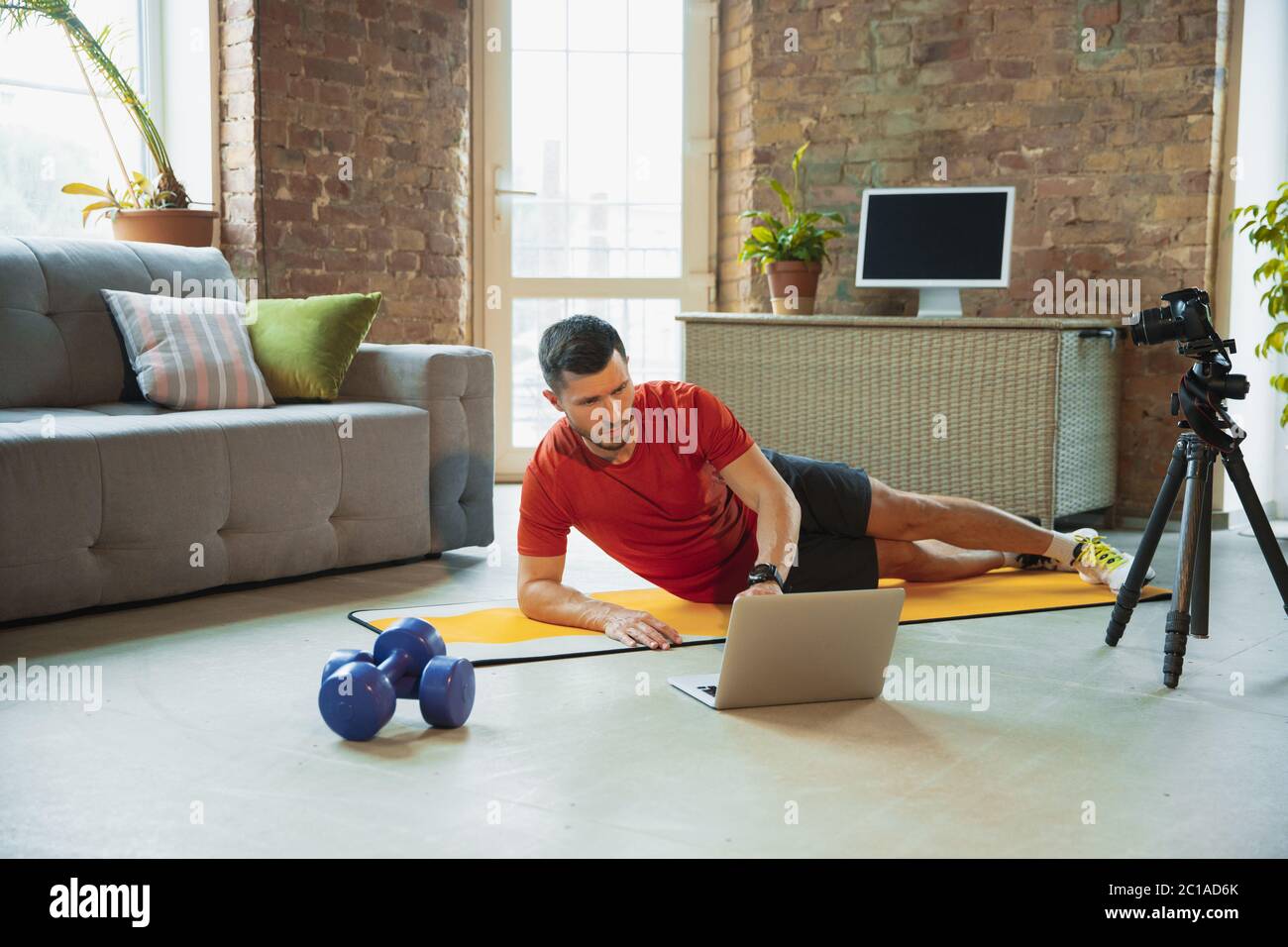 Stretching. Young caucasian man training at home during quarantine of ...
