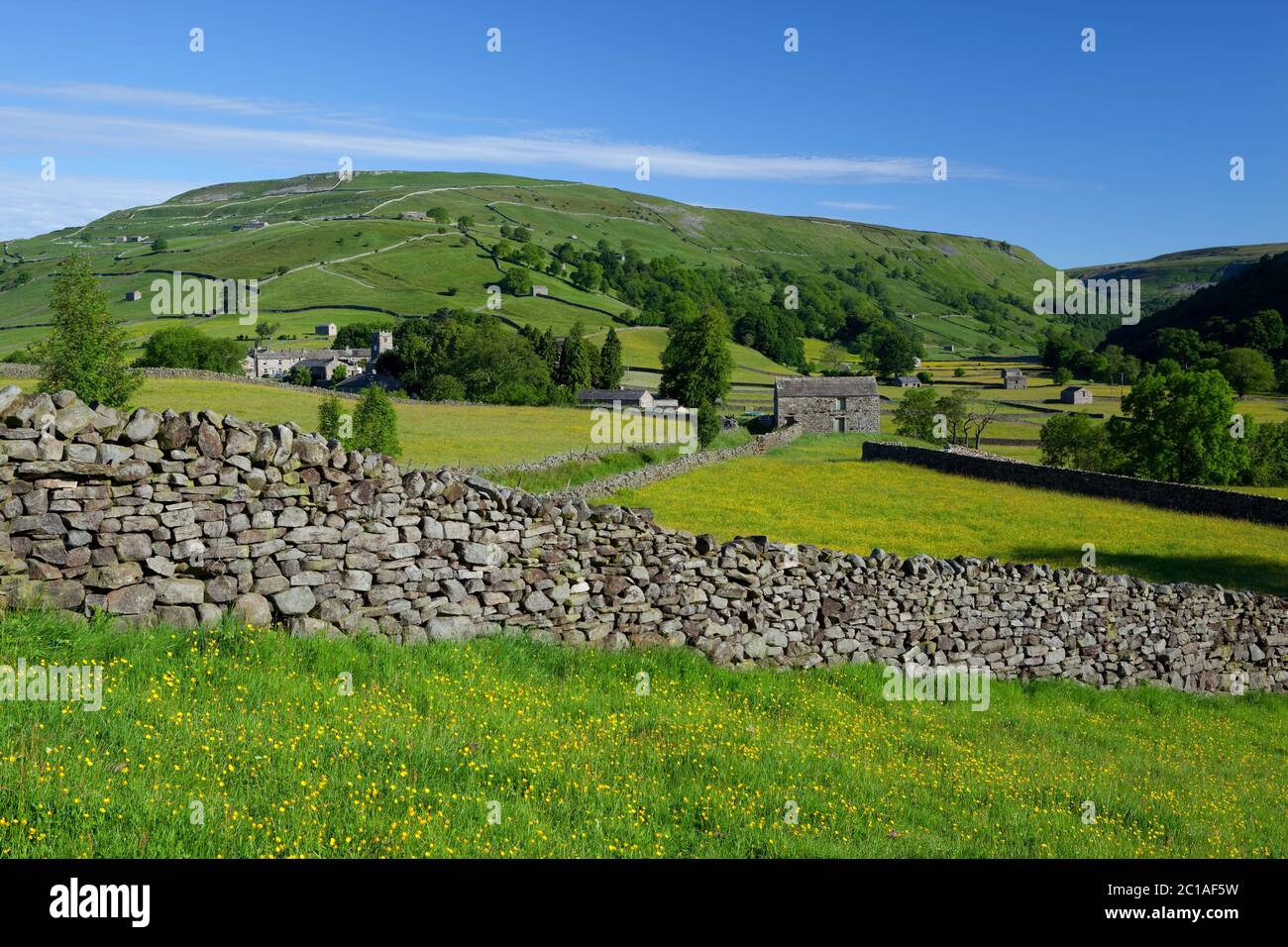 View over traditional dry stone wall and barn to the village of Muker ...