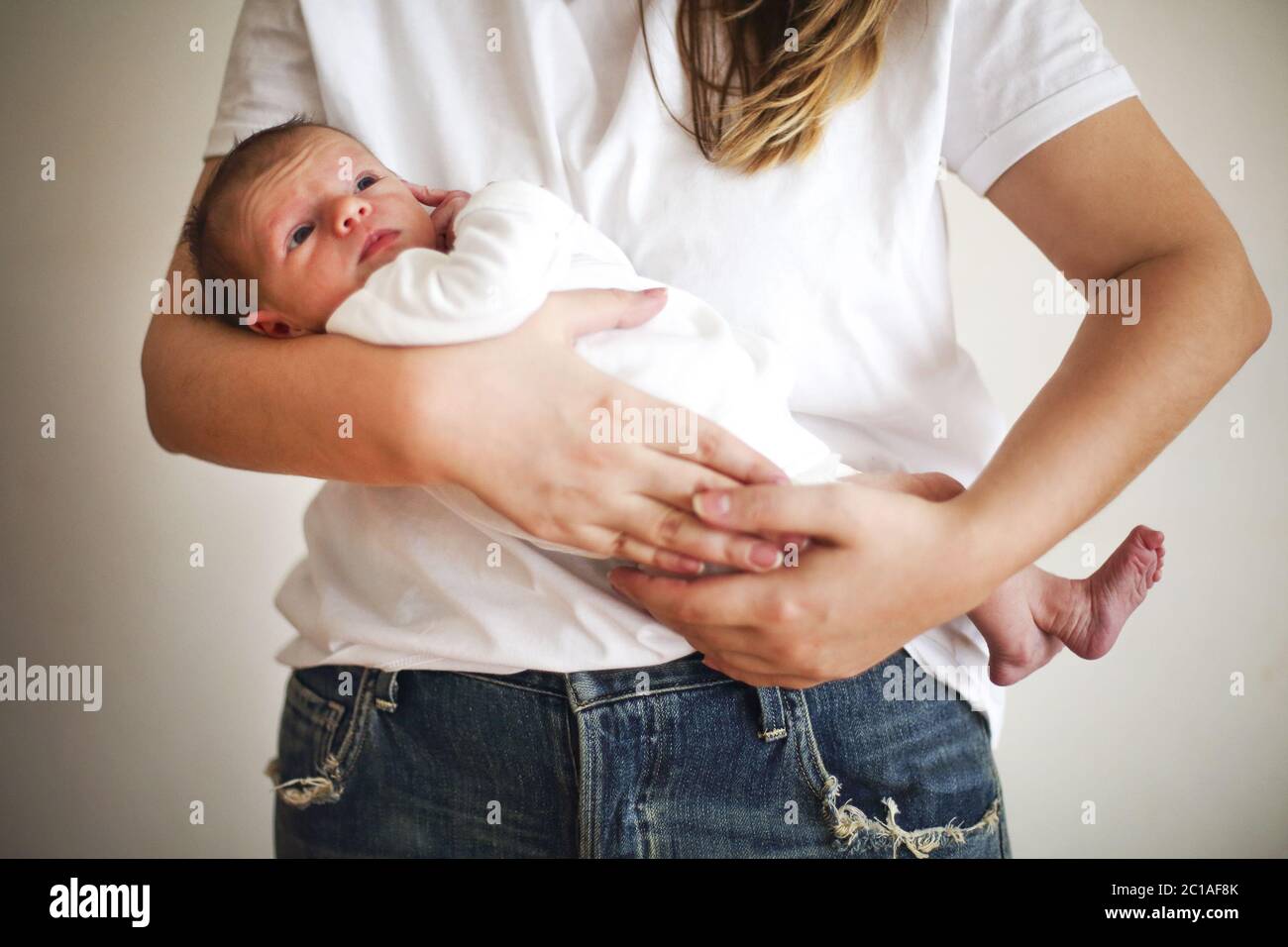 Young mother holding her newborn child. Mom nursing baby. Family at ...
