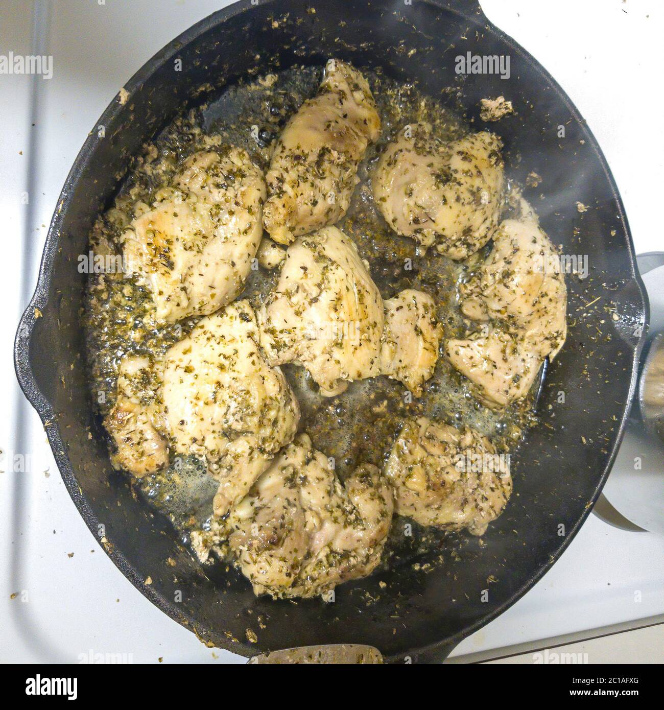 Square crop Slices of chicken meat with green herbs cooking on a hot ...