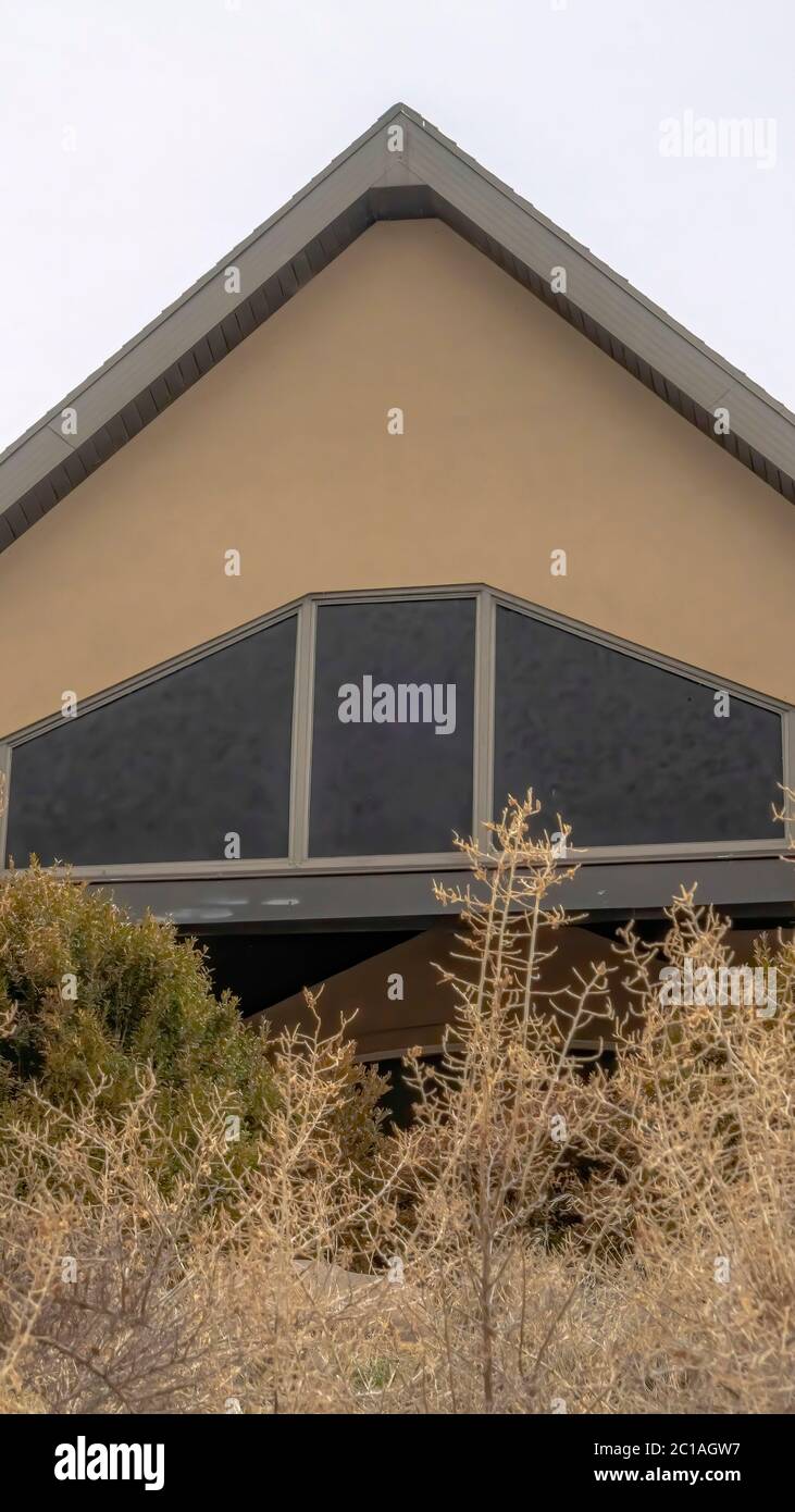 Vertical Home exterior with front gable roof at entrance viewed behind ...