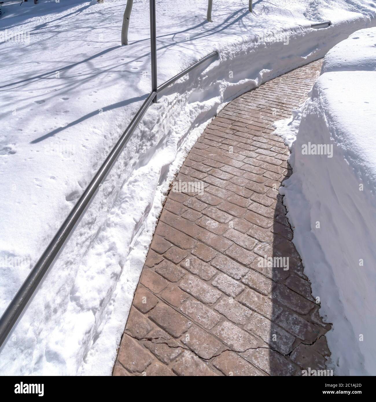 Square Stone brick pathway curving amid deep layer of fresh snow on a ...