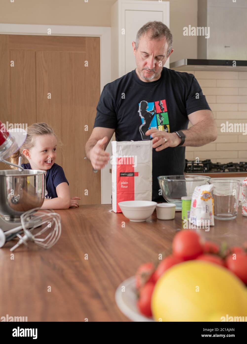 Daddy and daughter making fresh pizza dough in kitchen mixer. Corona ...