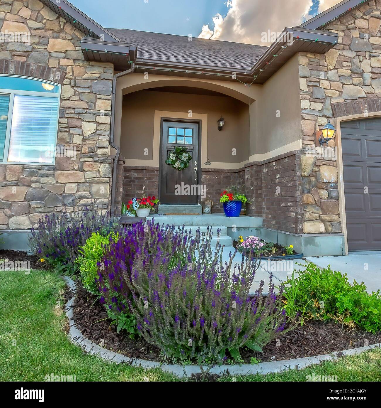 Square frame Facade of home with lush yard in front of stone wall and ...