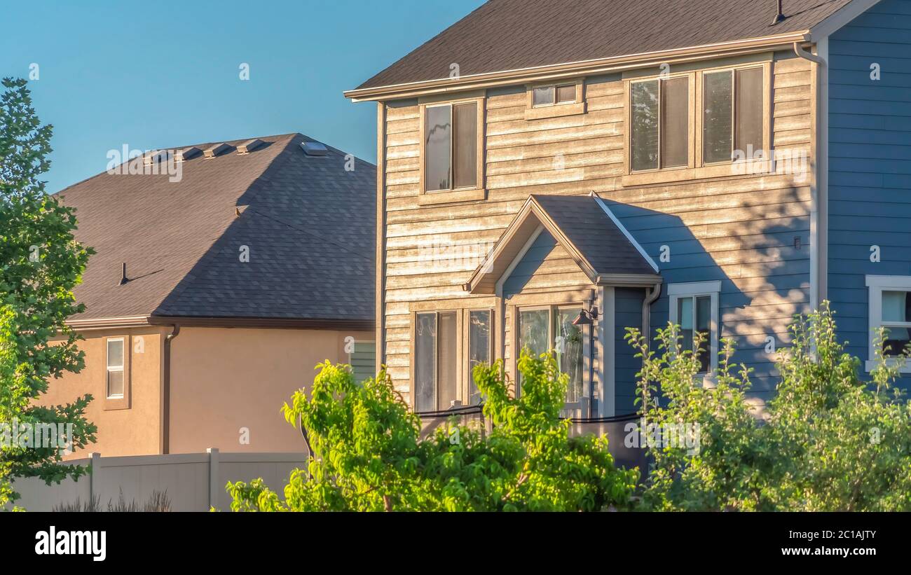 Panorama Sunny day view of home exterior with gray roof over sunlit ...