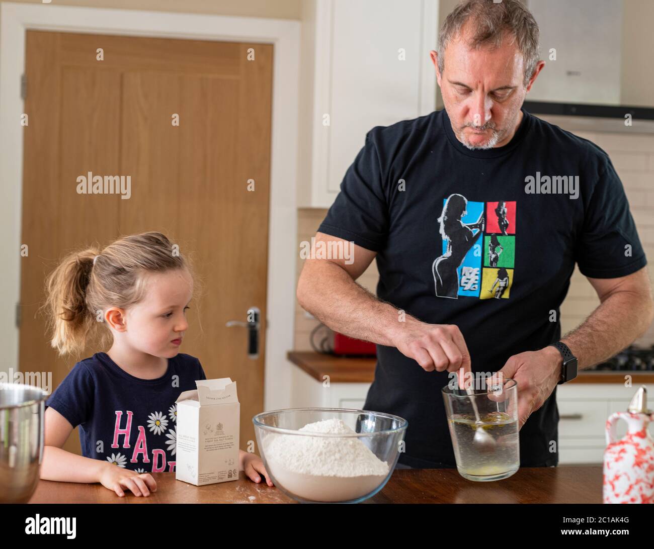 Daddy and daughter making fresh pizza dough in kitchen mixer. Corona ...