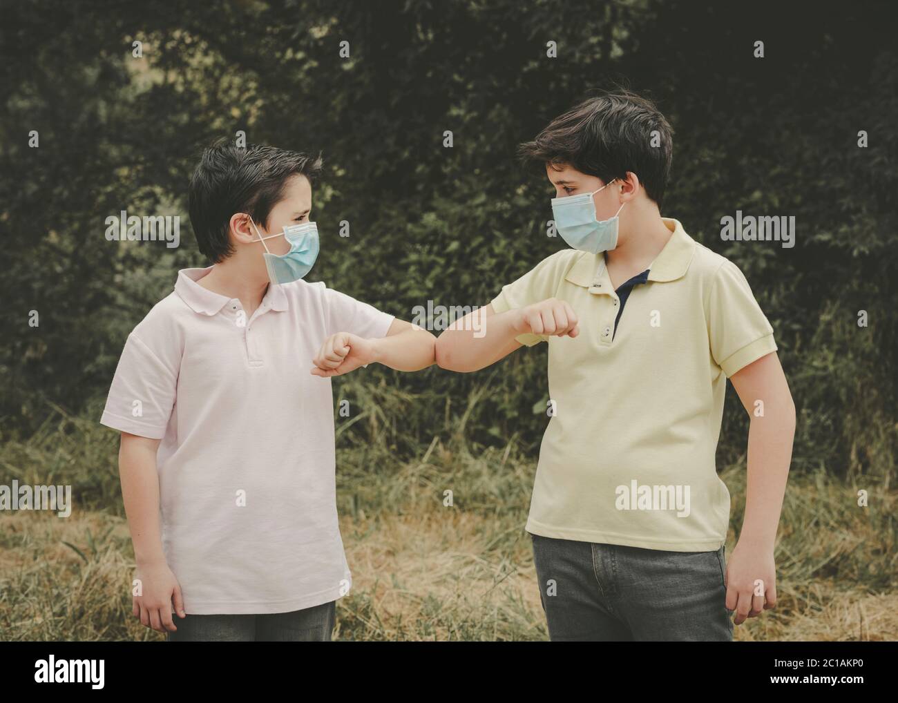 two kids with medical mask bump elbows, social distancing concept ...