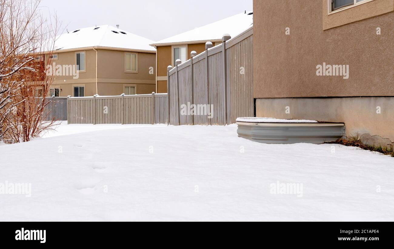 Panorama Ground blanketed with snow in front of houses and woodne fence ...