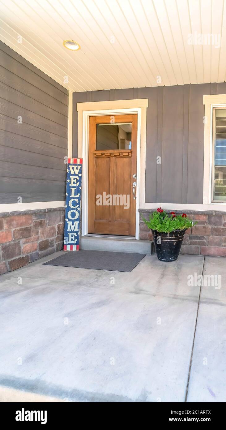 Vertical Home entrance with concrete porch brown wooden front door ...