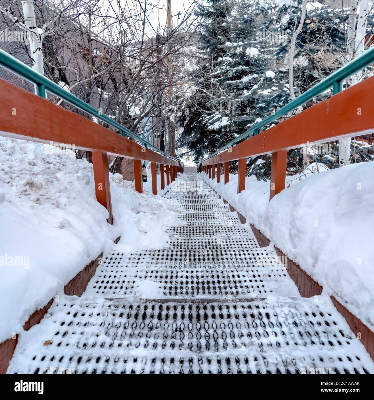 Square Grate tread stairs with wood and metal hansrail against snowy ...