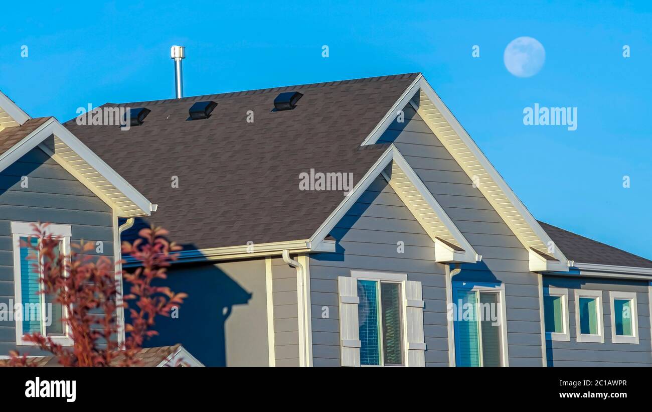 Panorama Sunlit home with dark pitched roof over horizontal gray wall ...