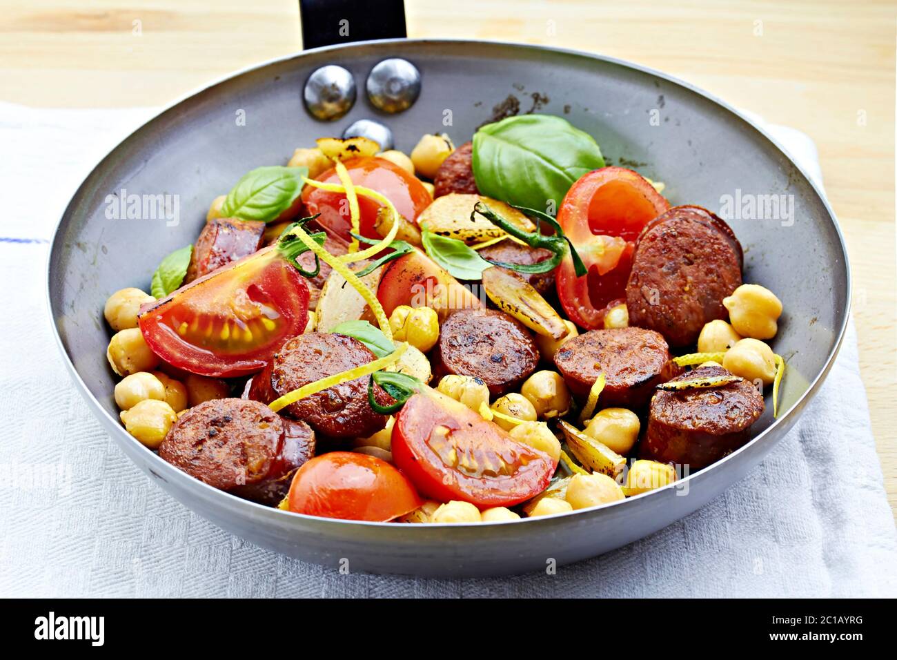 Fried chorizo, chickpeas, tomato, lemon rind and basil on pan Stock ...