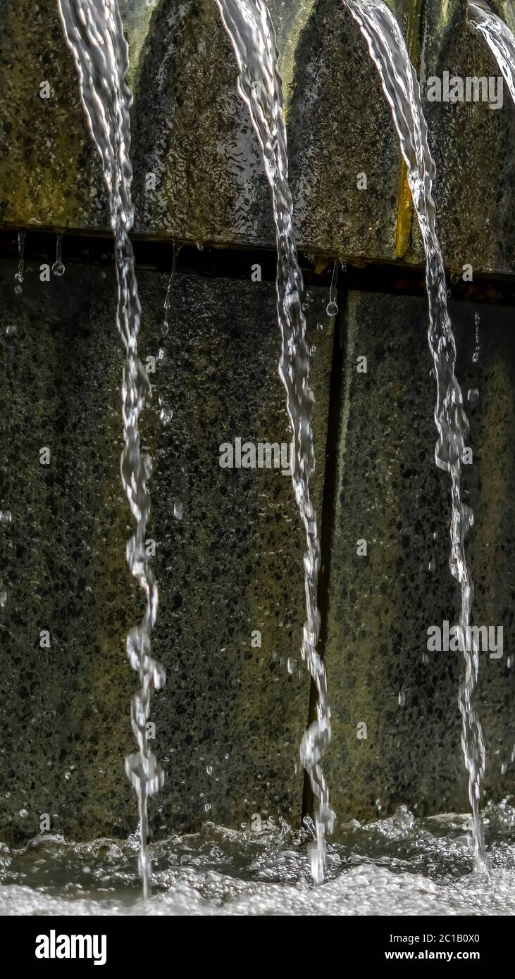 Vertical crop Cicular stone fountain pool with trickling clear water in ...