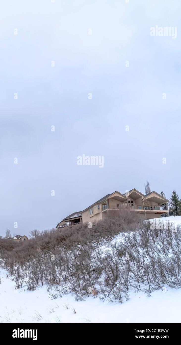 Vertical crop Homes atop gentle hill slopes with fresh snow and ...