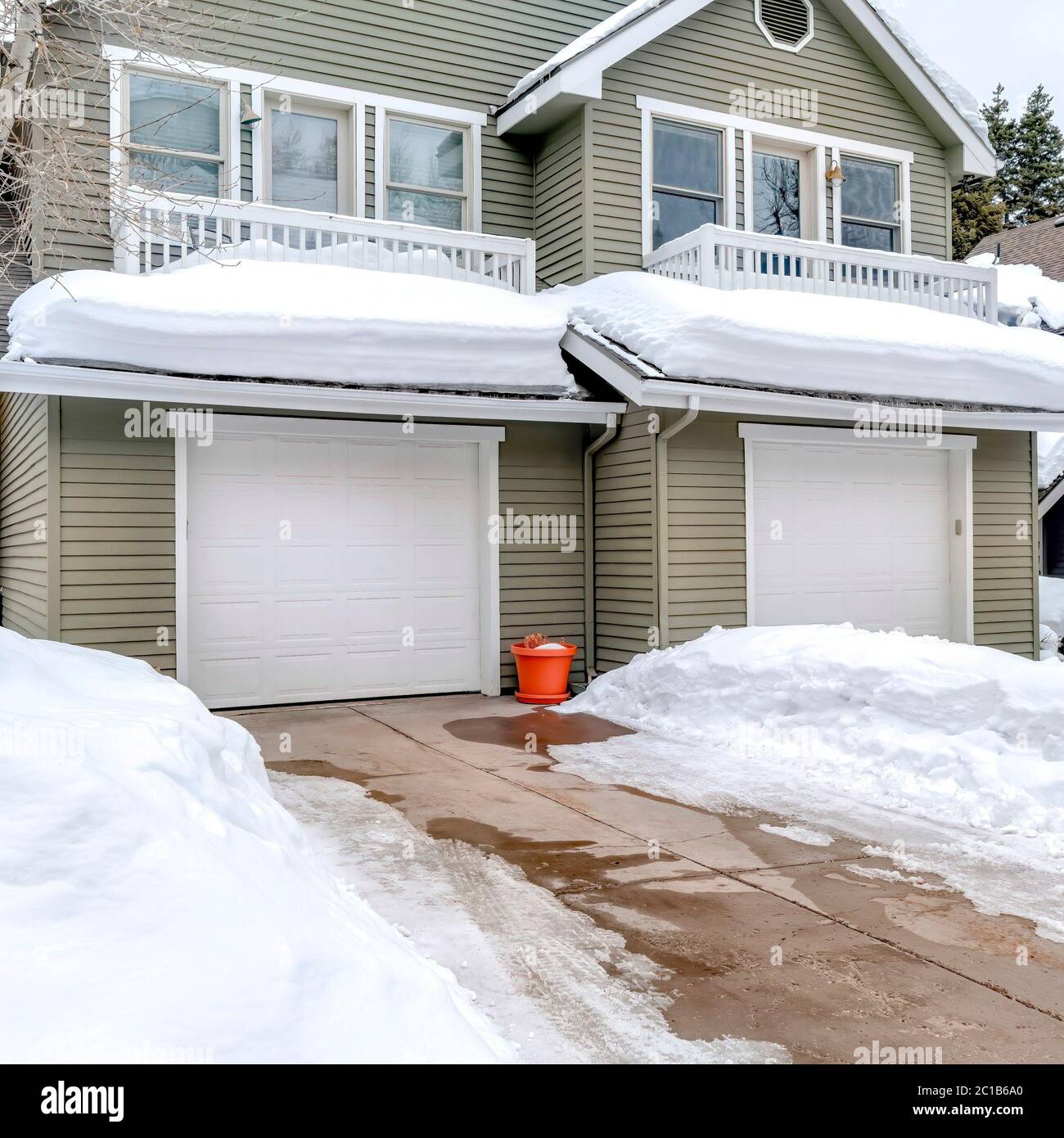 Square crop Facade of home with snowy driveways in front of two car ...