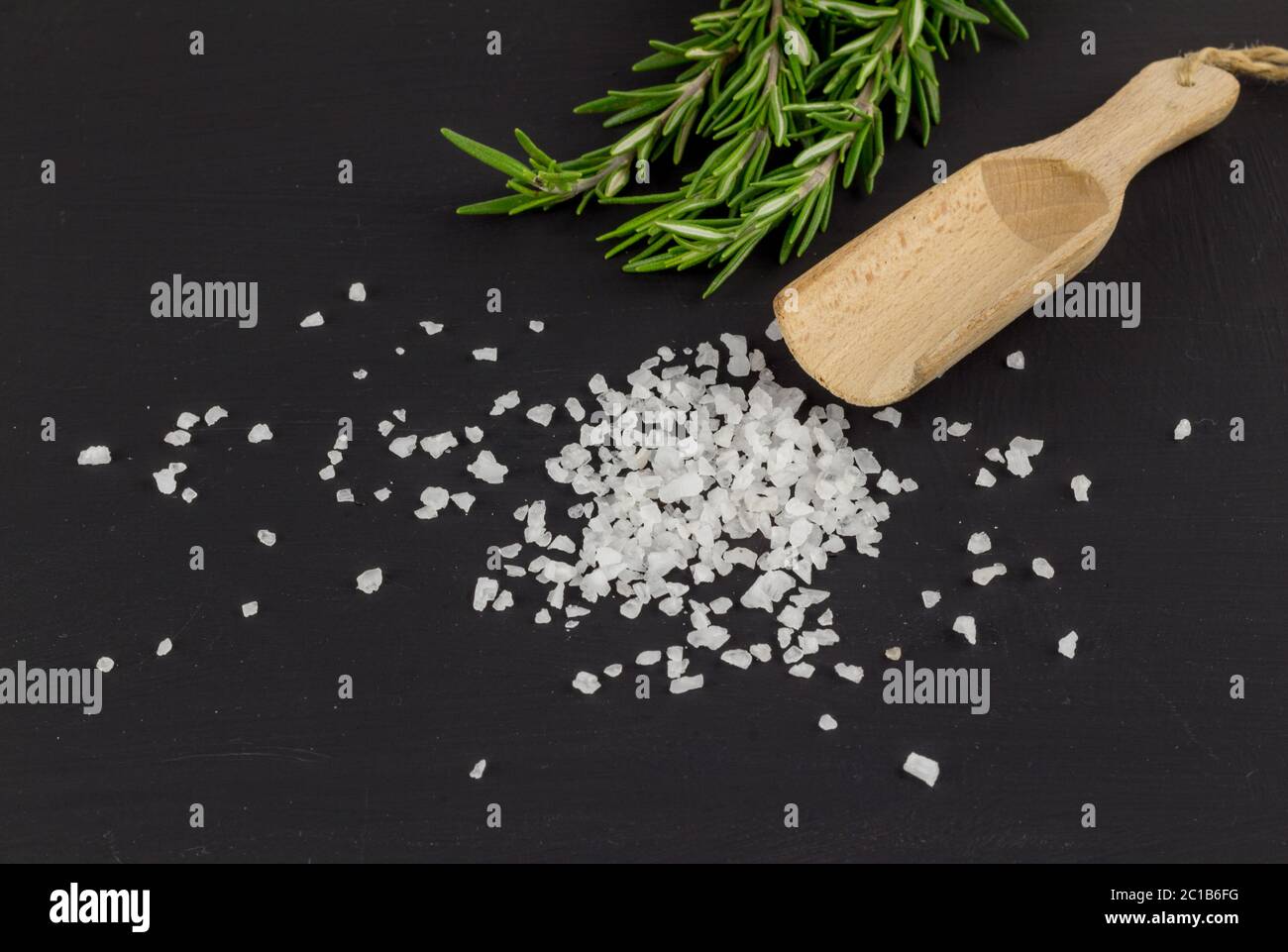 Salt heap on rustic black background with rosemary herb and wooden ...
