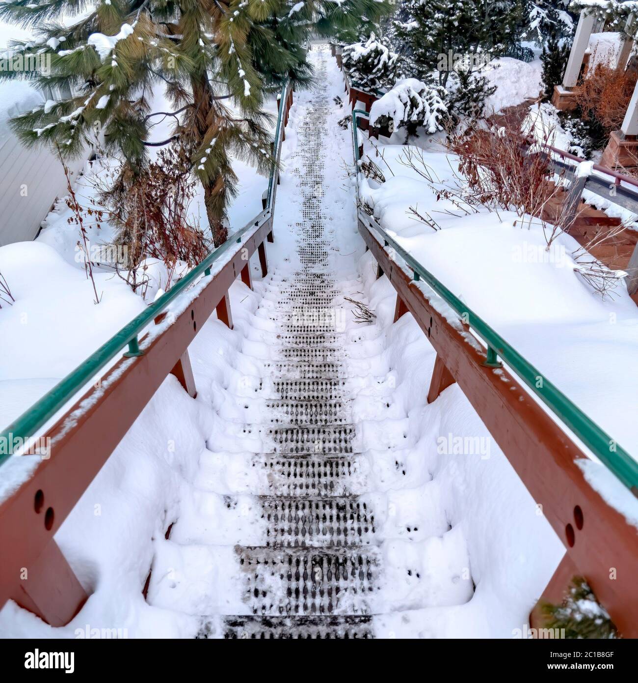 Square Grate metal tread stairway on hill slope blanketed with snow ...