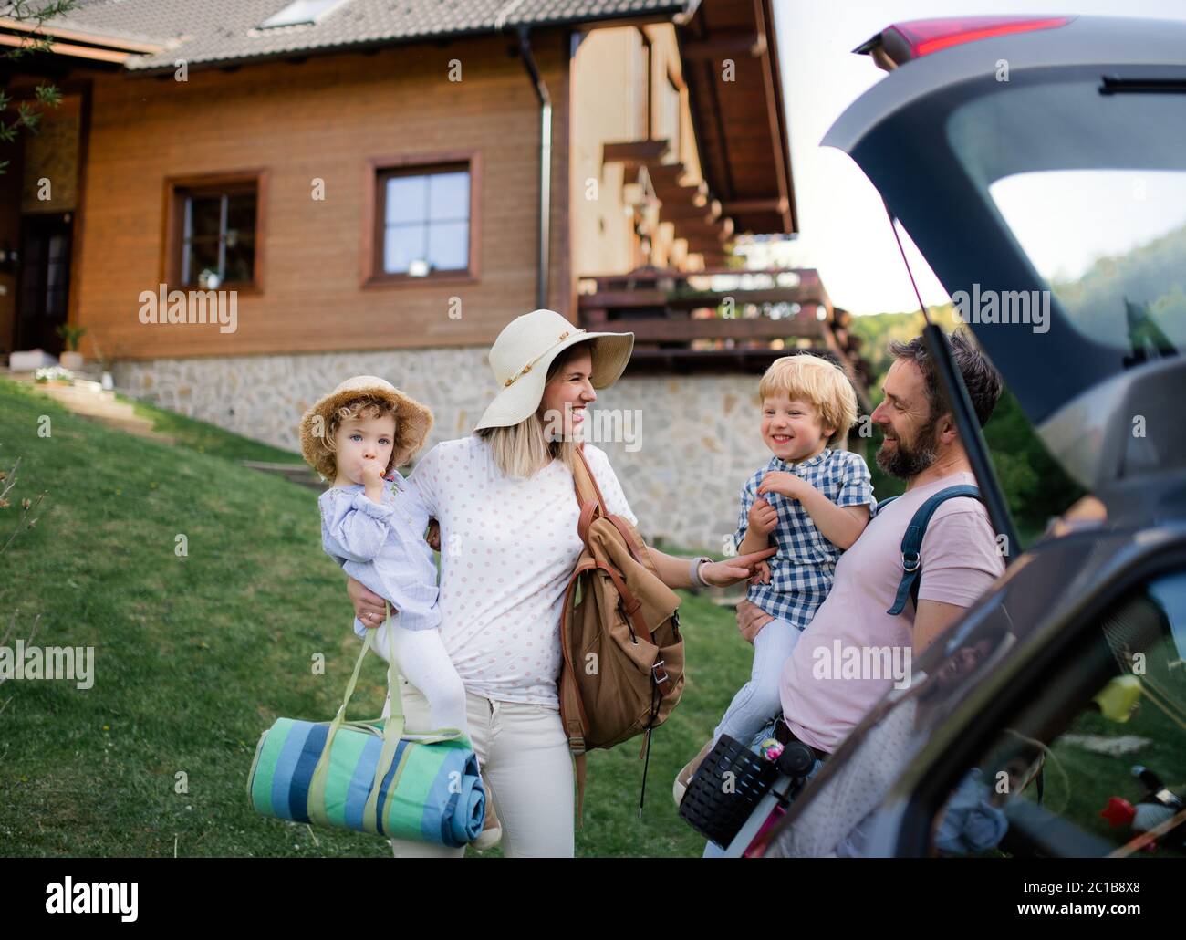 Family with two small children loading car for trip in countryside ...