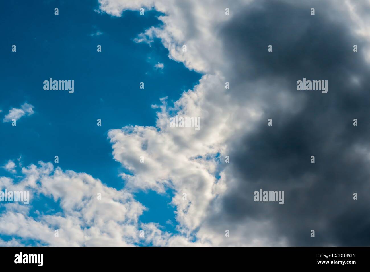 Bright blue sky with dark raincloud forming overhead, outdoors in ...
