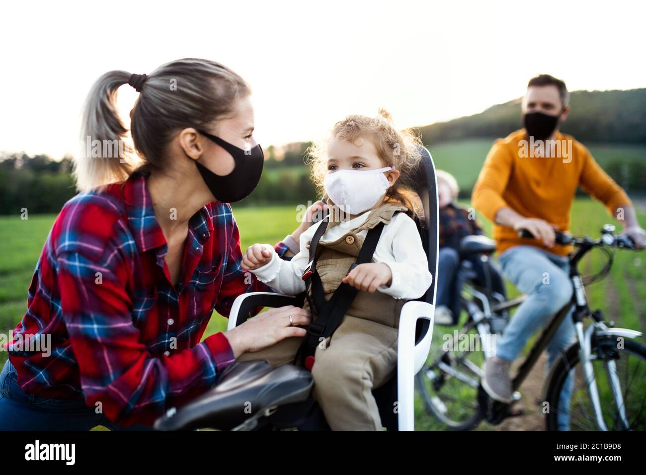 Family with two small children on cycling trip, wearing face masks ...