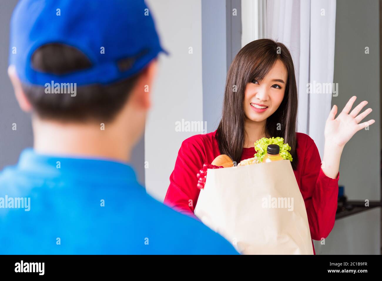 Asian young delivery man in blue uniform making grocery service giving ...
