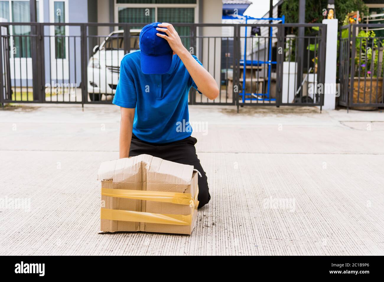 Asian young delivery man in blue uniform he emotional falling courier ...