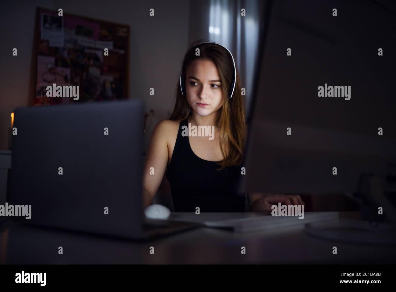 Bored young girl with computer sitting indoors, online chatting concept ...