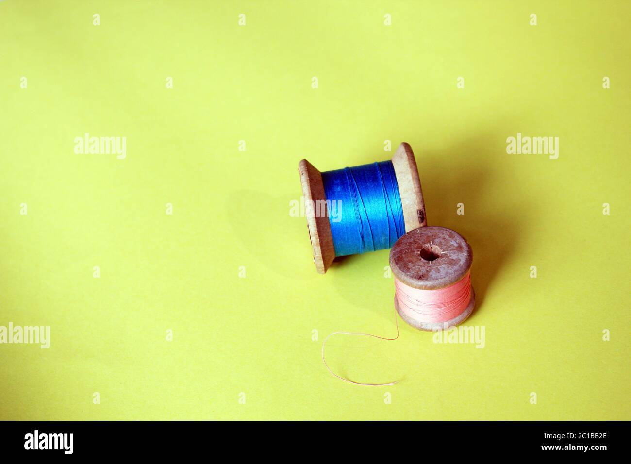 cotton thread reels bobbin pink and blue on bright background with copy ...