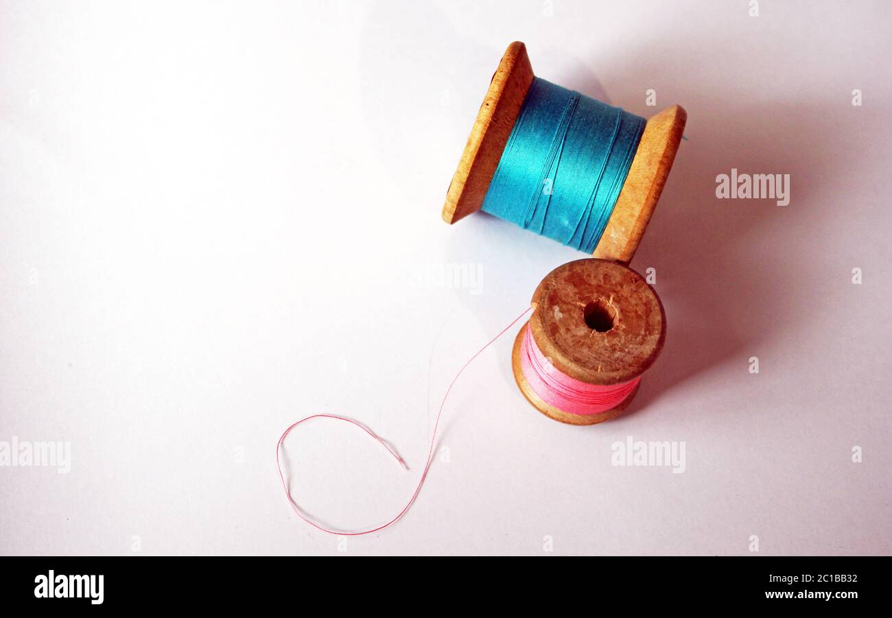 cotton thread reels bobbin pink and blue on bright background with copy ...