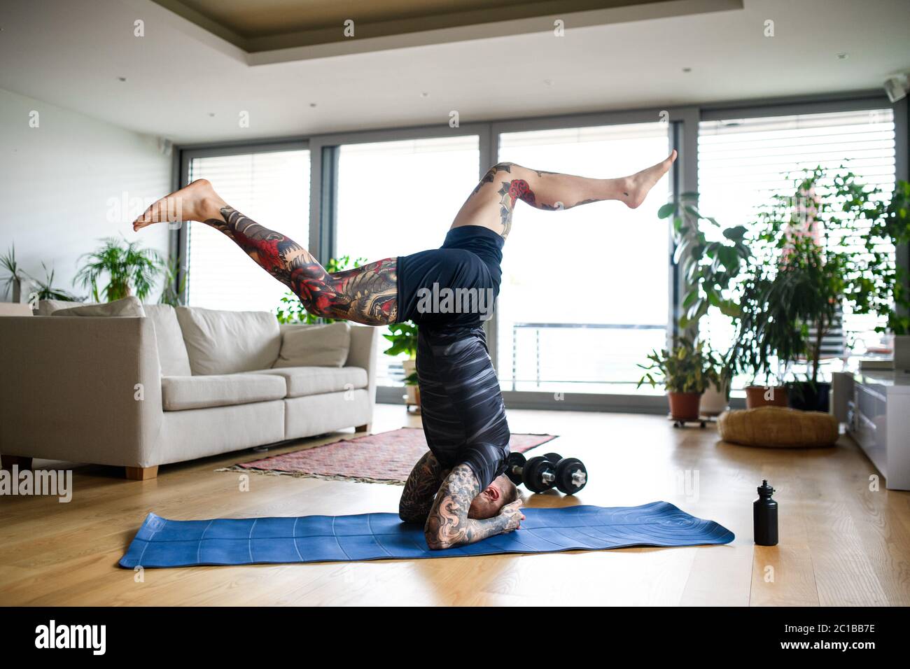 Young man doing workout exercise indoors at home, headstand Stock Photo ...